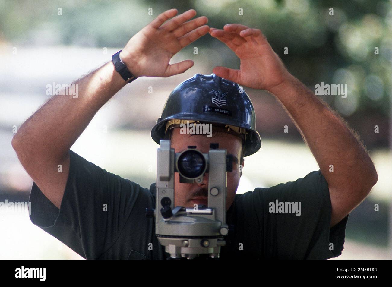 A Seabee of Construction Battalion Unit 402 (CBU 402) uses a tripod ...