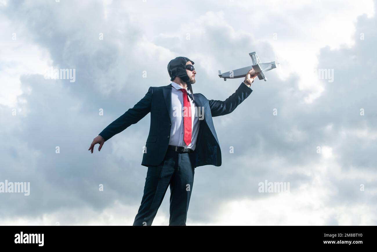 businessman in suit and pilot hat launch plane toy on sky background ...