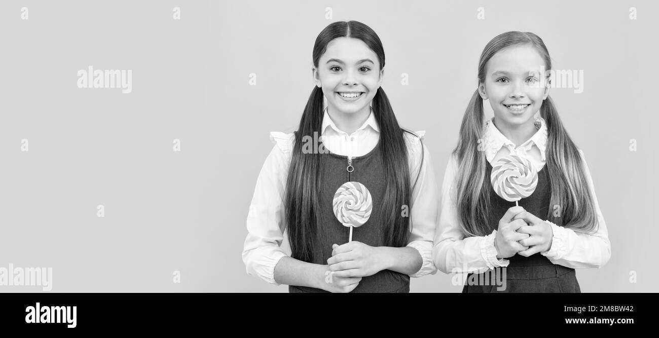 Happy kids in school uniforms hold lollipops yellow background ...
