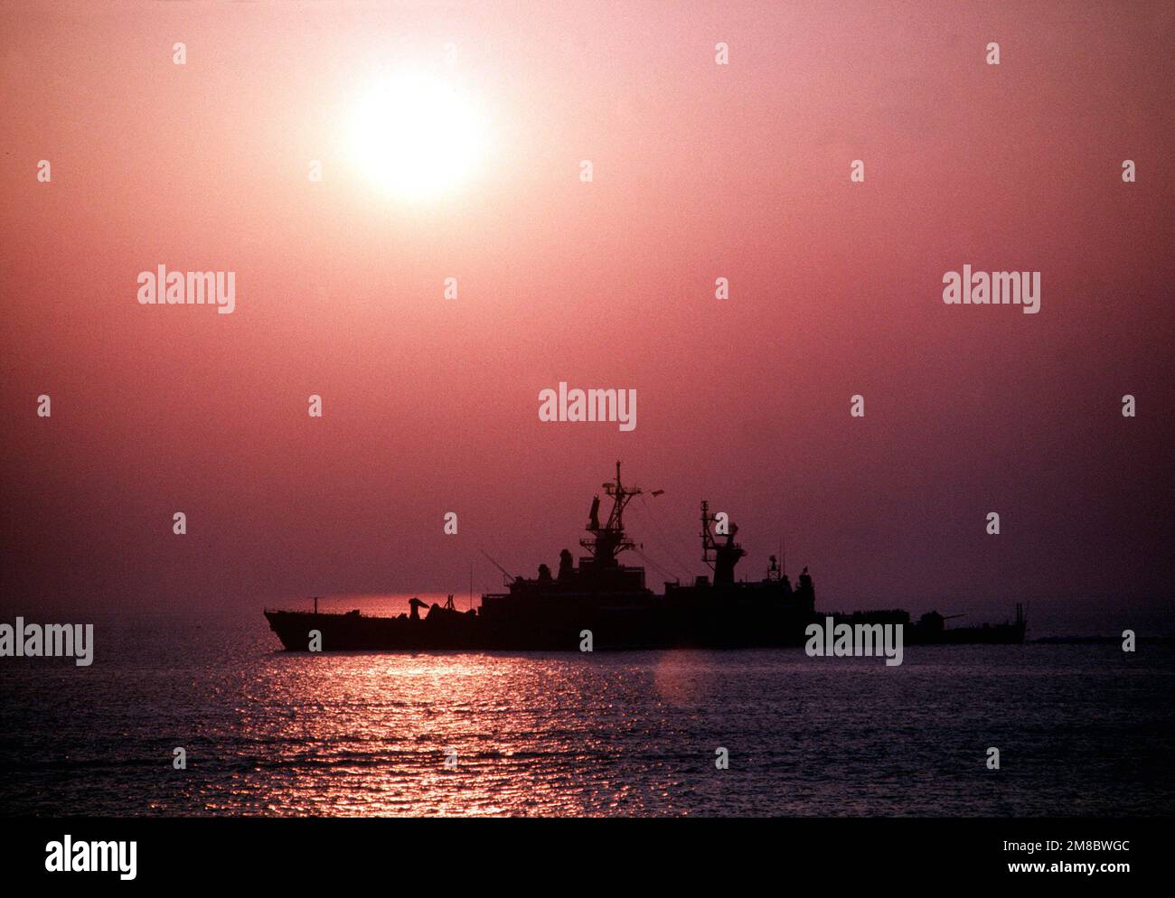 The guided missile cruiser USS BELKNAP (CG 26) is silhouetted against ...