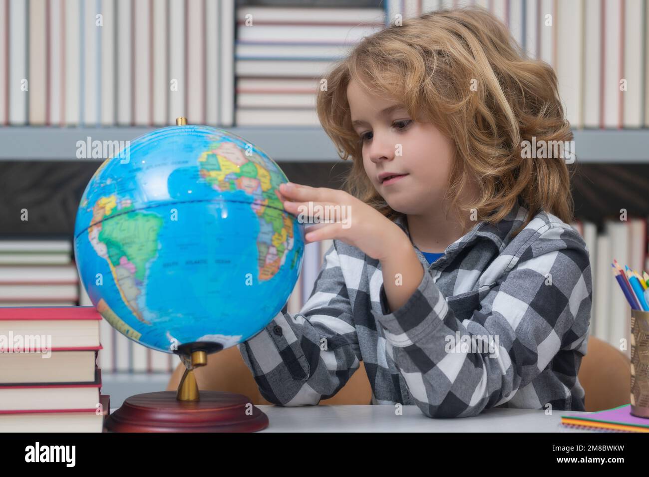 School pupil looking at globe in library, geography lesson. School ...