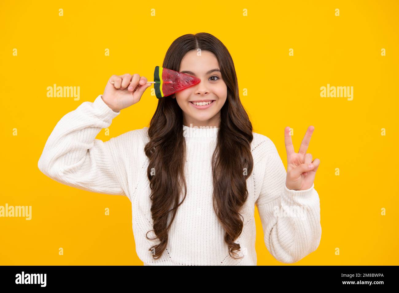 Cool teen child with lollipop over yellow isolated background. Sweet ...