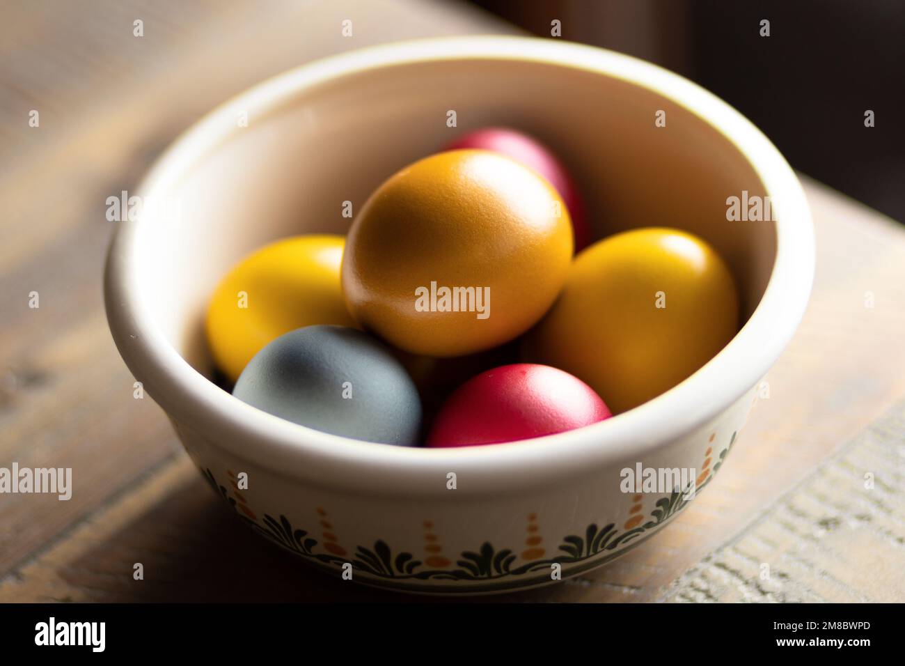a round bowl with an ornament, in which bright colored Easter eggs lie ...