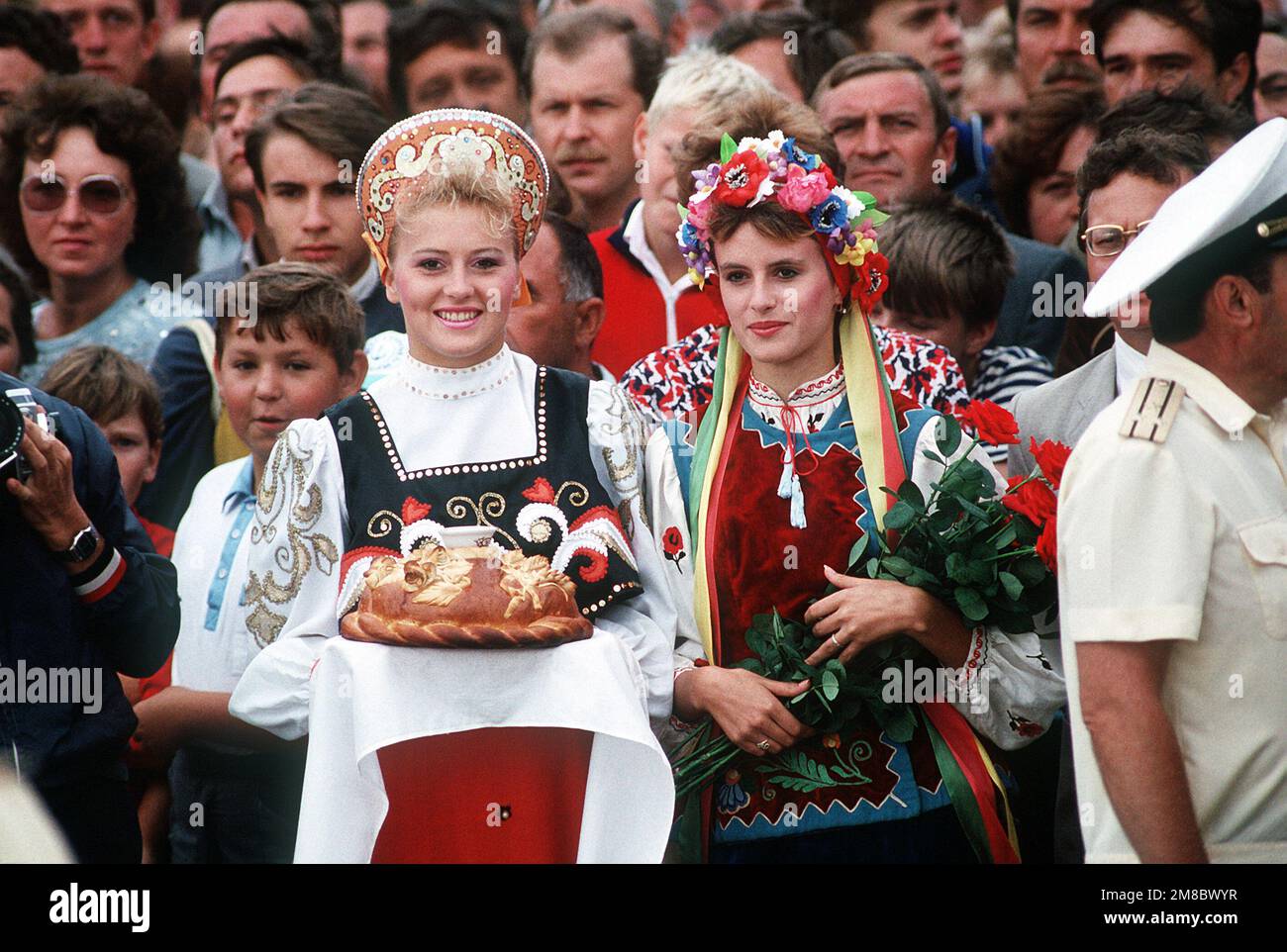 Two young Ukrainian women in traditional costume bring bread and roses ...