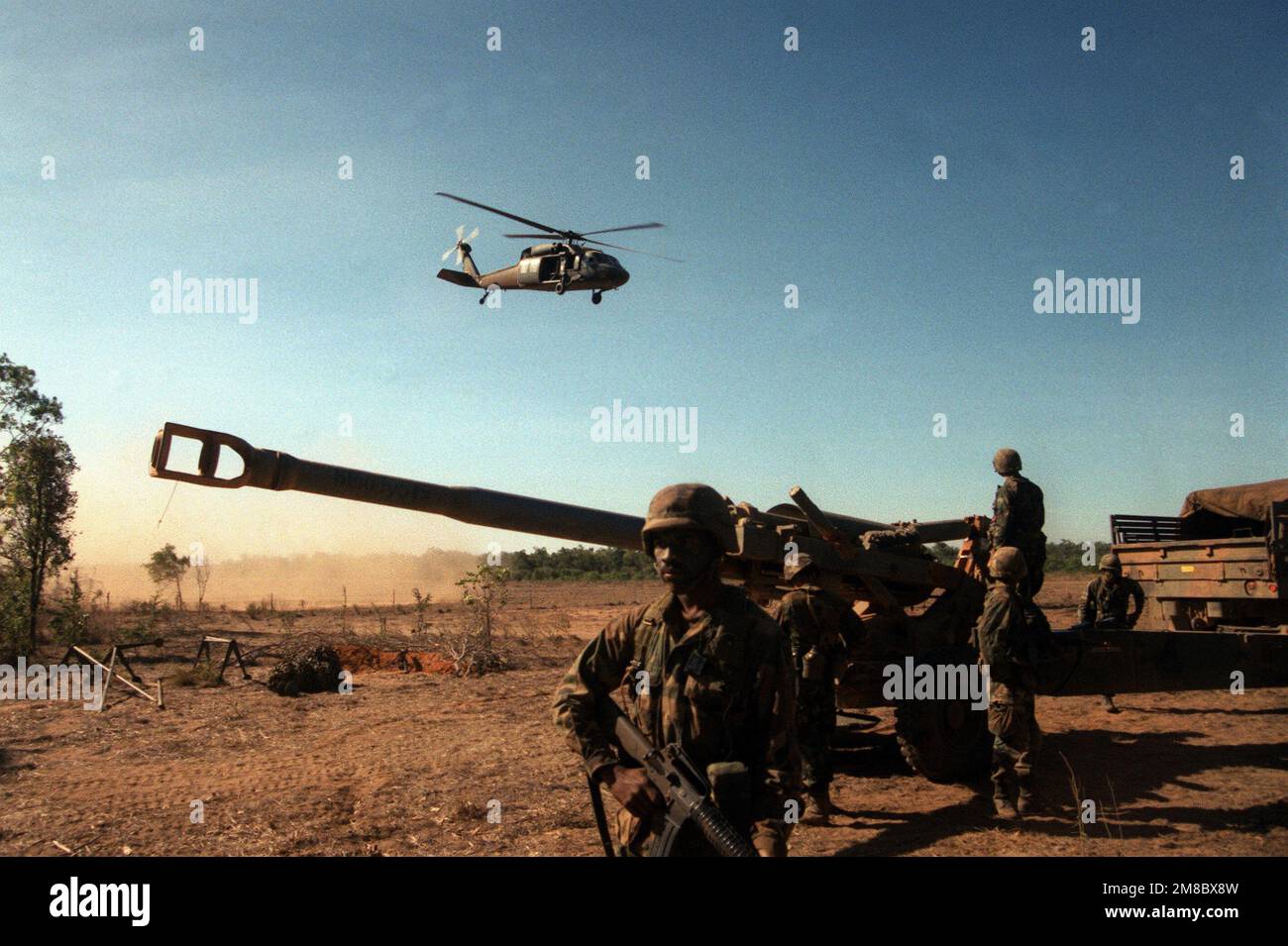 A UH-60 Black Hawk helicopter passes overhead as artillery operating in ...