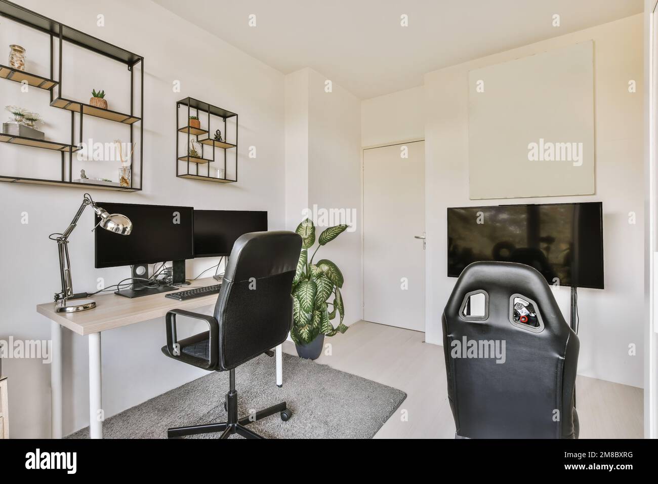 a home office with two computer desks and a large monitor on the wall ...