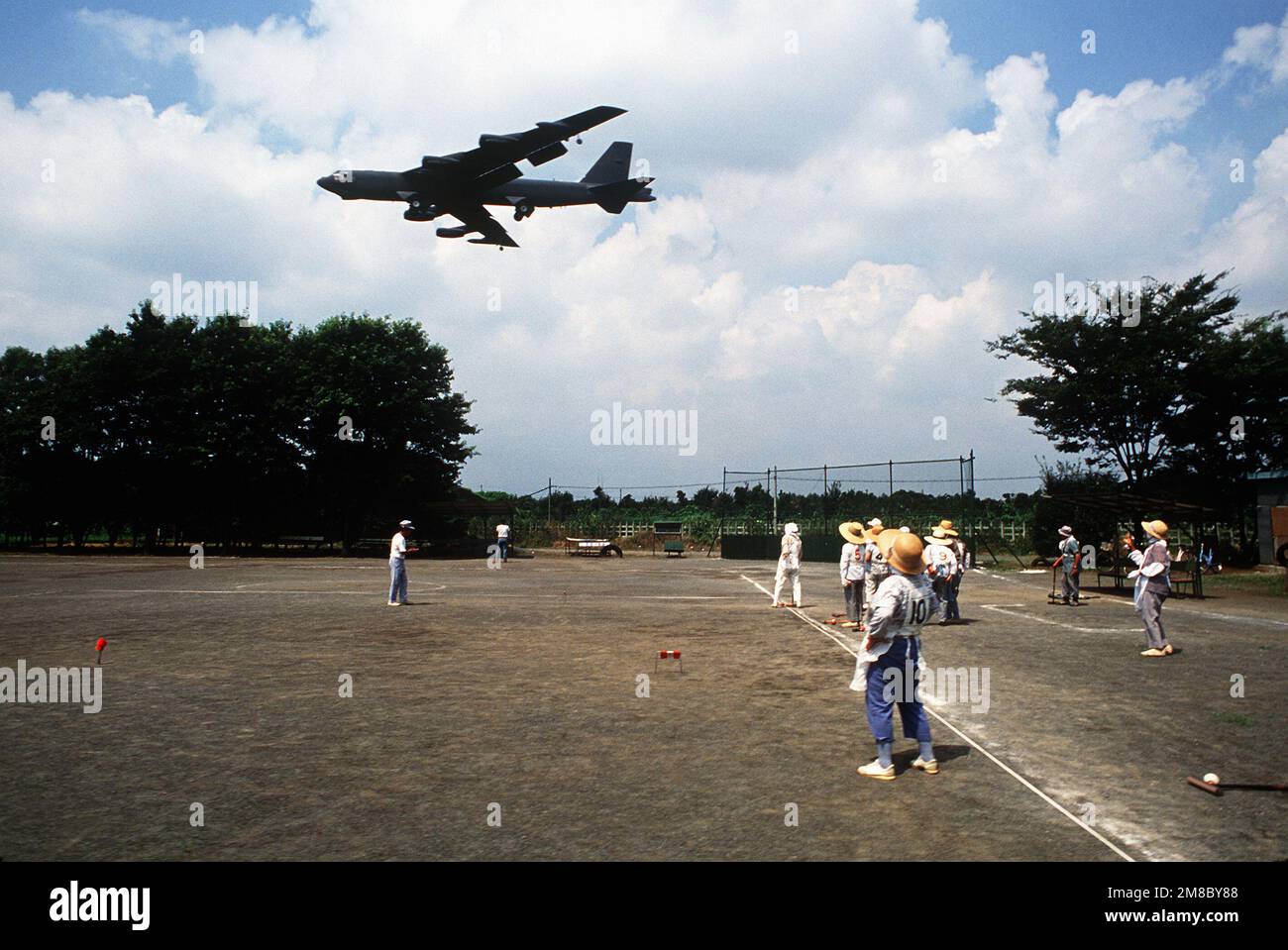 Japanese civilians pause during a game to watch a B-52G Stratofortress ...