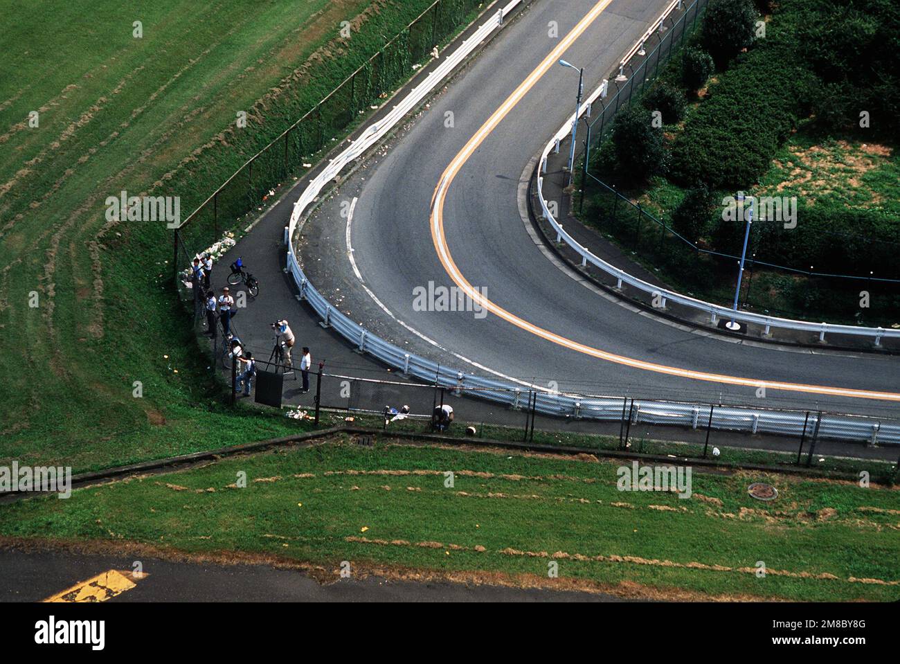 Japanese civilian photographers stand at the base's perimeter fence to ...
