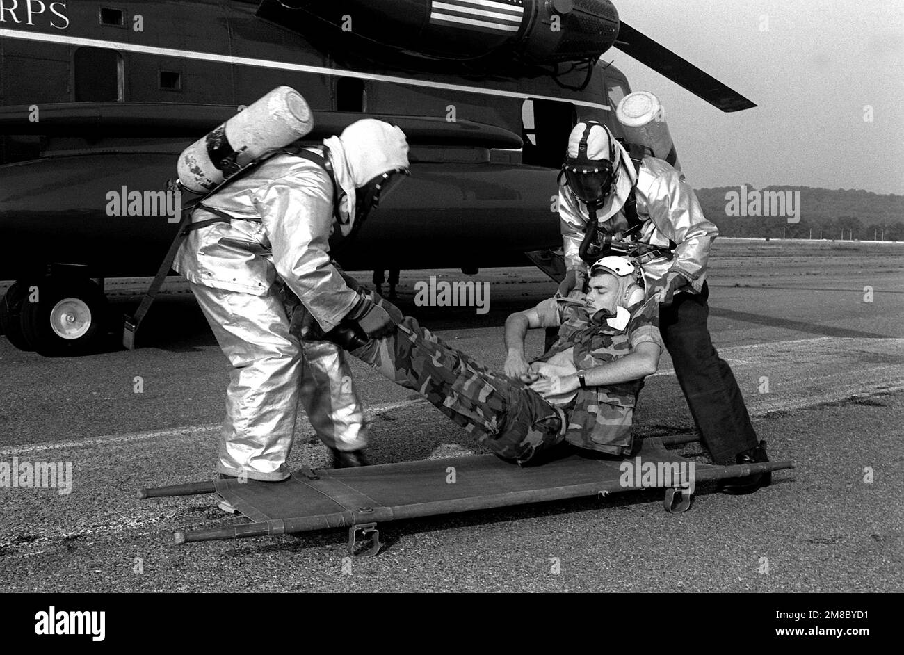 Members of a crash/fire rescue squad move a patient away from a CH-53 ...