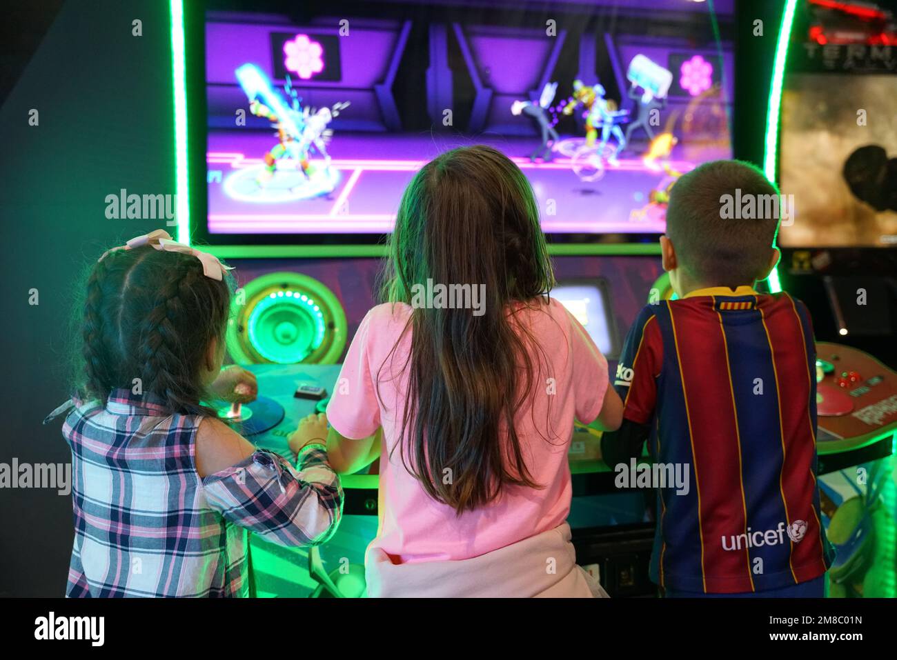 Three kids playing an arcade game together Stock Photo - Alamy