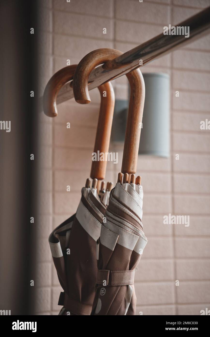 A vertical closeup of two umbrellas hanging from a metal bar Stock ...
