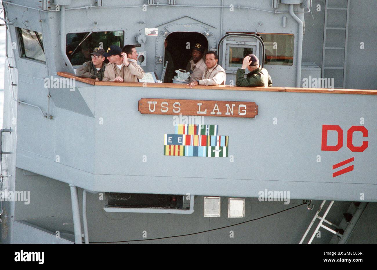 Crew members aboard the frigate USS LANG (FF 1060) watch from the ...