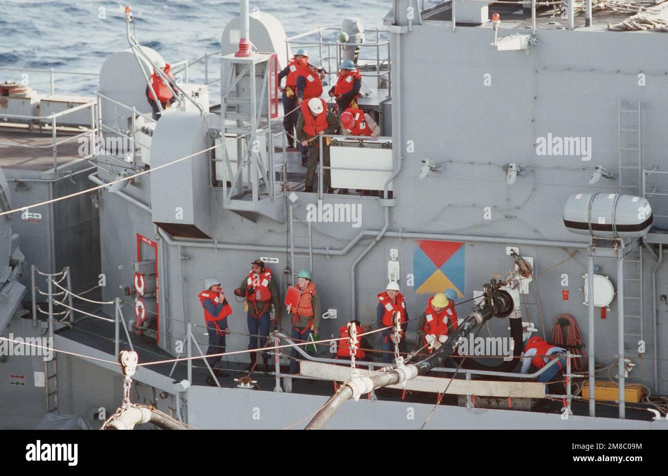 Crew members aboard the frigate USS LANG (FF 1060) stand by a refueling ...