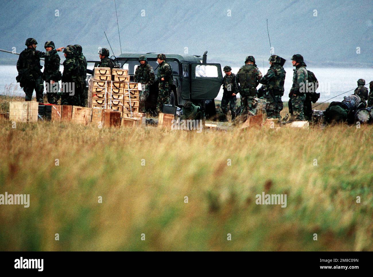 Crates of ammunition sit stacked on the ground near an M998 high ...