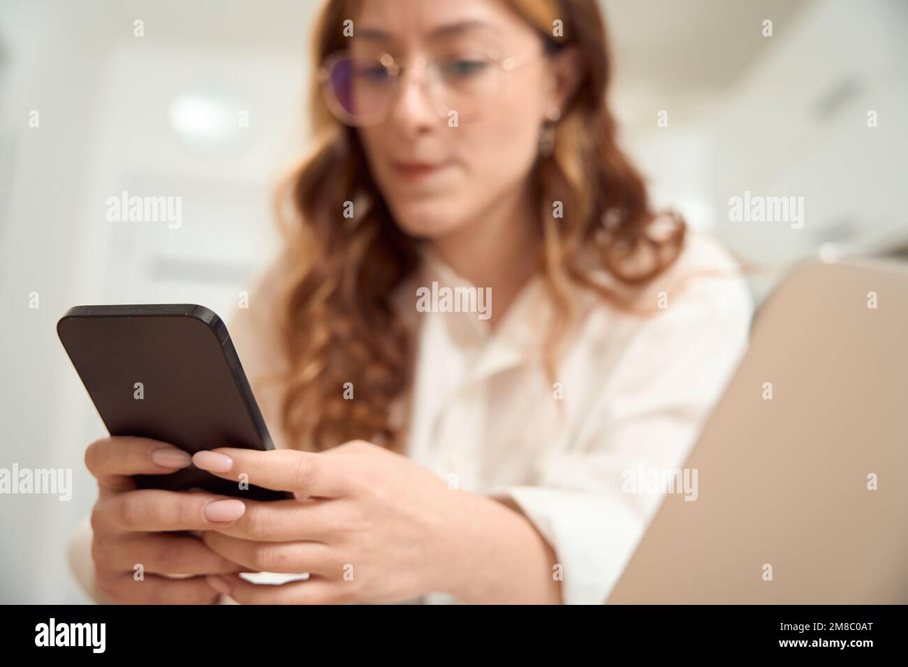 Concentrated female tapping with both hands on smartphone touch screen ...