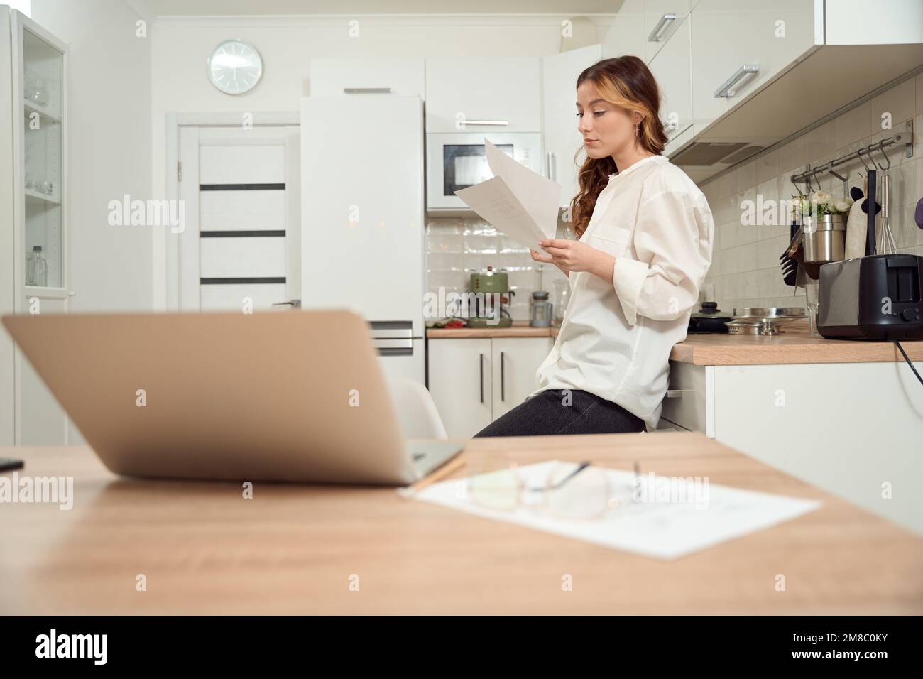 Focused female looking through documents at home Stock Photo - Alamy