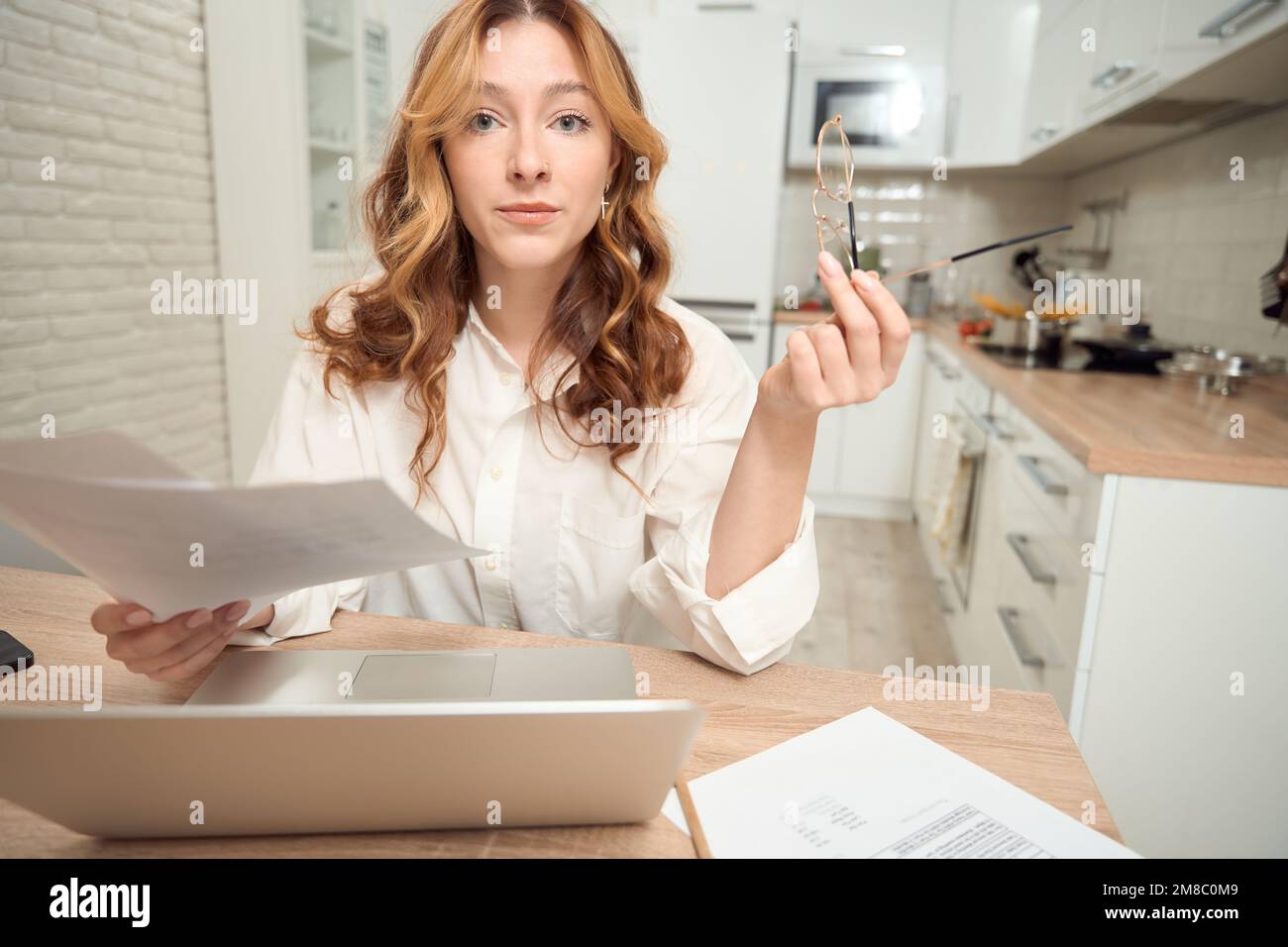 Serene female with papers seated at laptop Stock Photo - Alamy