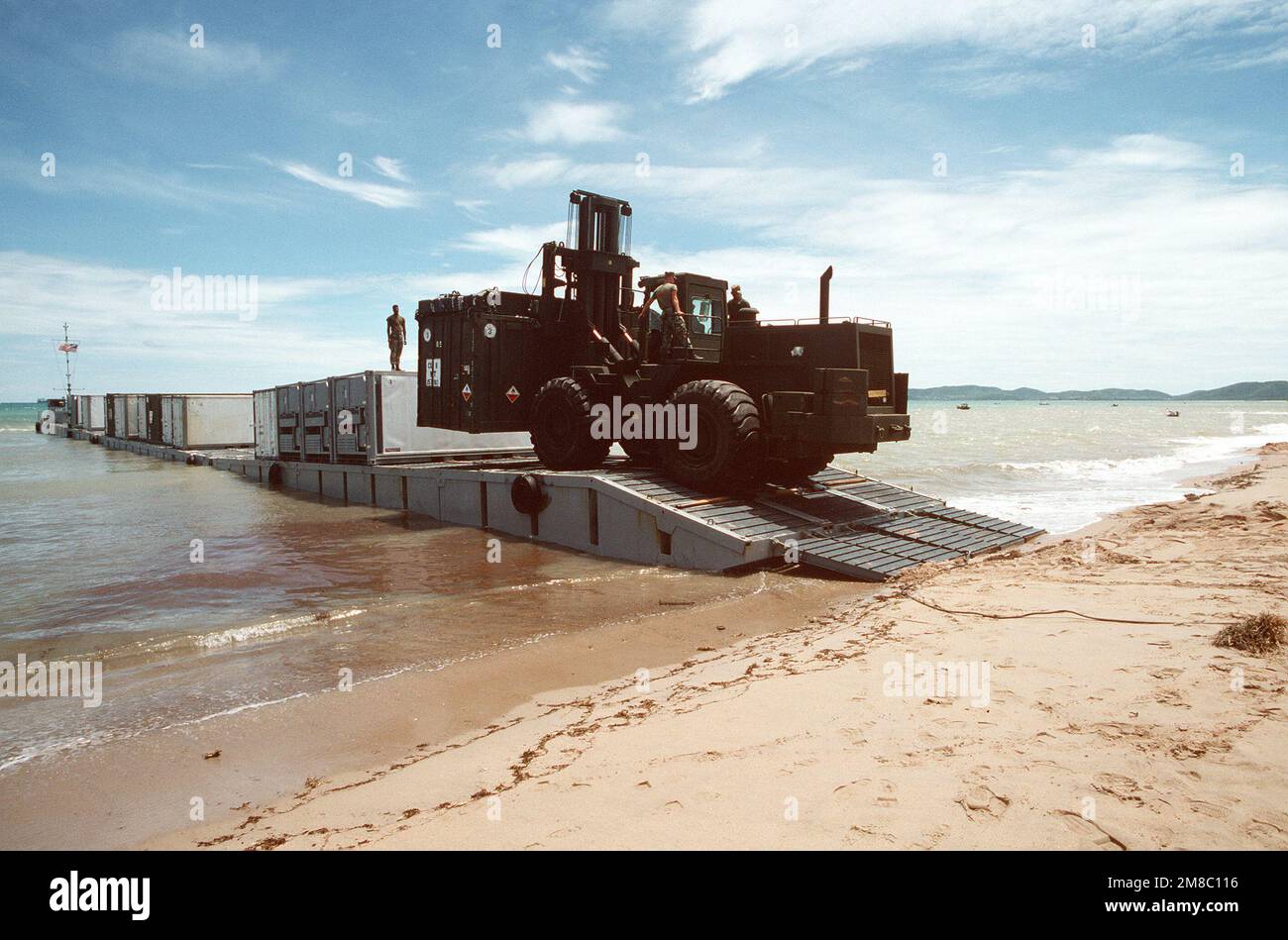 A forklift picks up CONEX containers from a causeway to transport them ...