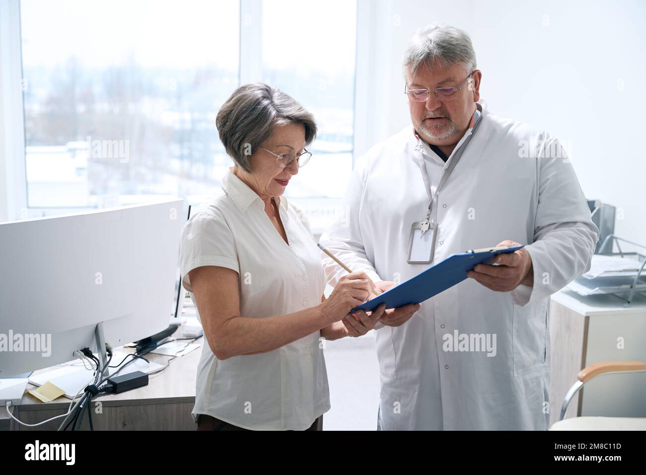 Elderly patient signs documents in the doctor office Stock Photo - Alamy