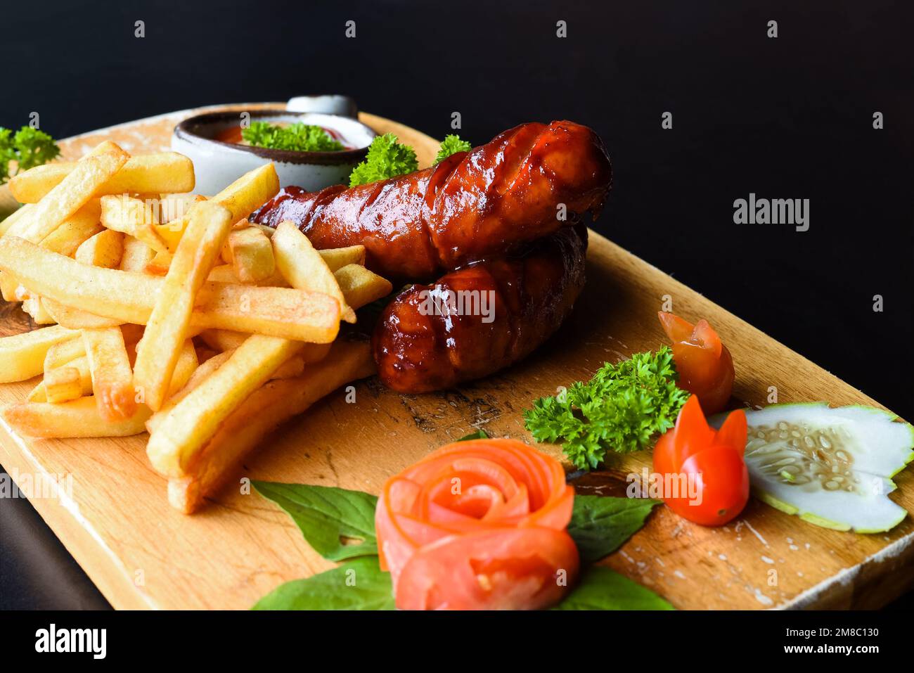 Fried sausages with french fries and spicy sauce on wooden board ...