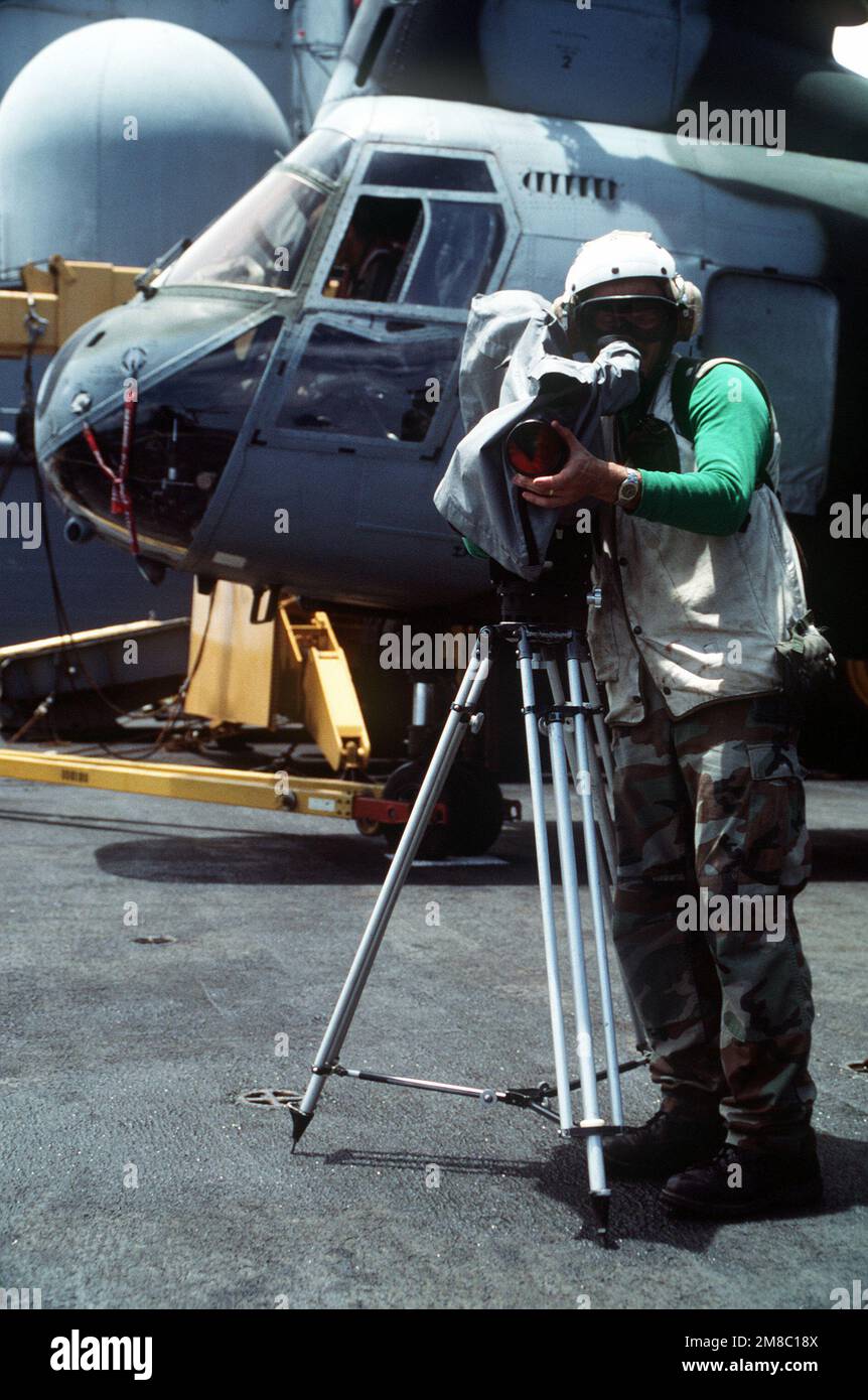 A video cameraman focuses his camera set near a CH-46E Sea Knight ...