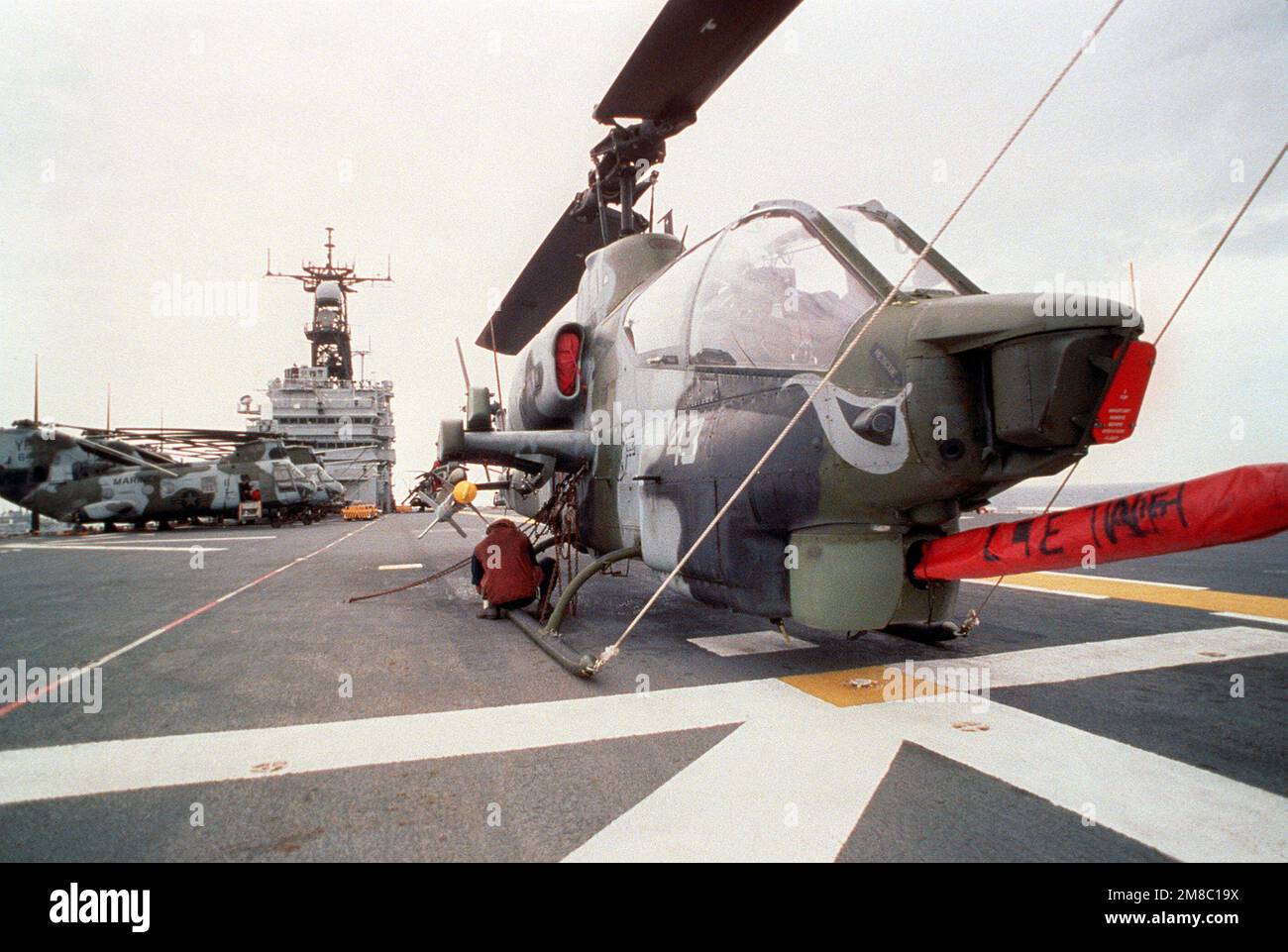 An AH-1W Sea Cobra helicopter armed with an AIM-9 Sidewinder missile, foreground, and several CH ...