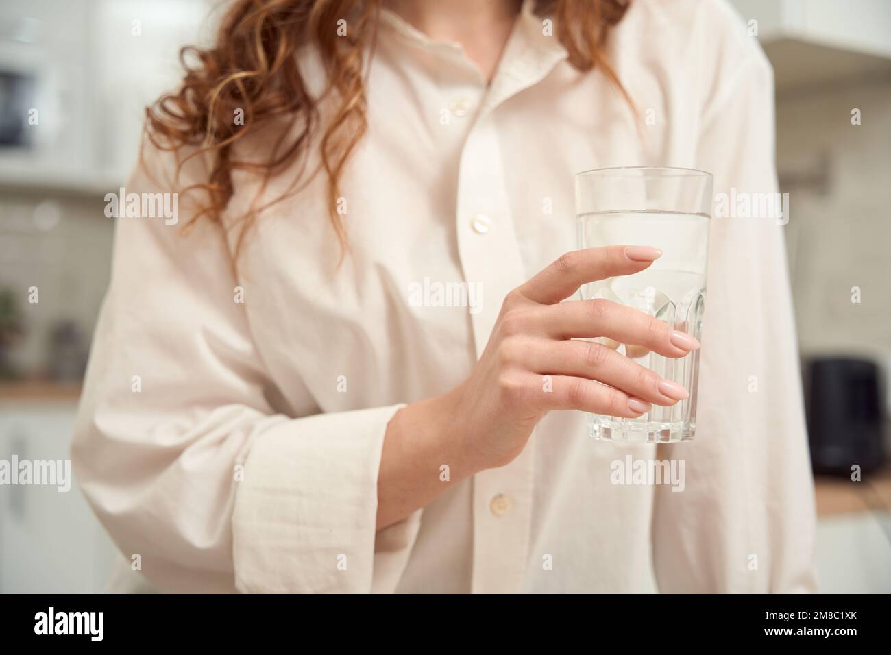 Female person drinking transparent liquid in kitchen Stock Photo - Alamy