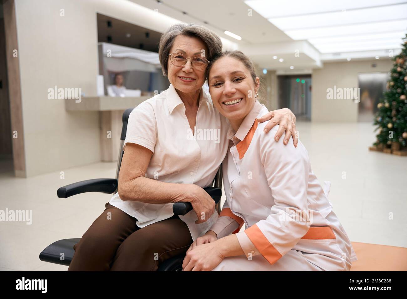 Happy female patient in wheelchair hugging her rehabilitator Stock ...
