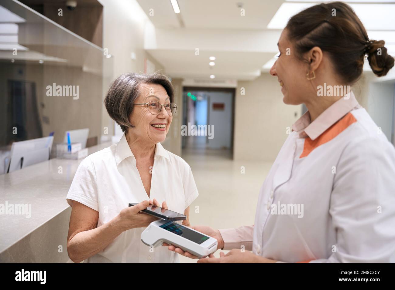 Elderly woman pays for her visit to therapist using phone Stock Photo ...