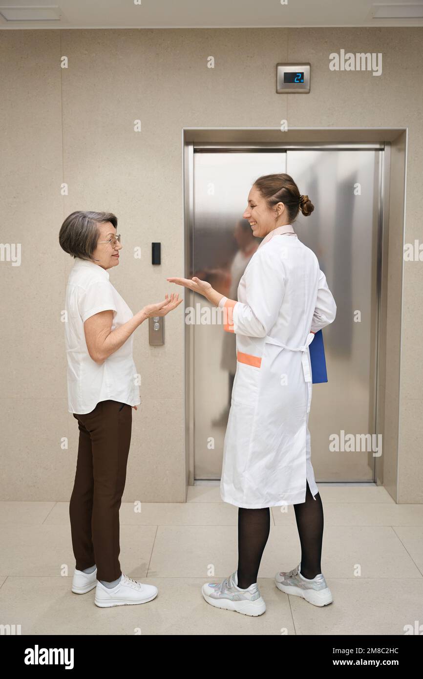 Two women are standing by elevator in lobby of clinic Stock Photo - Alamy