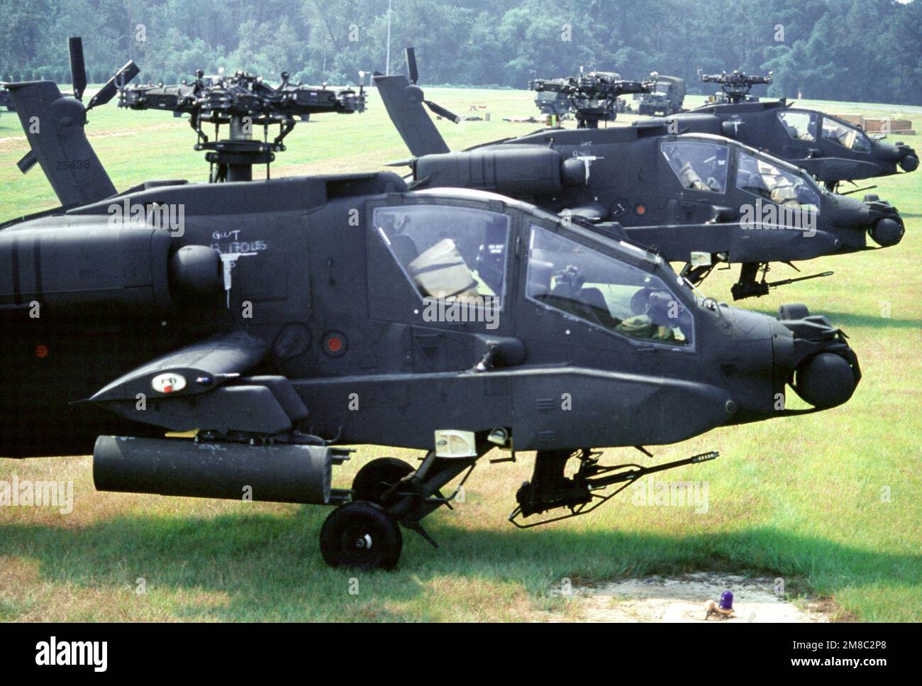 Three AH-64A Apache helicopters, their main rotor blades having been ...