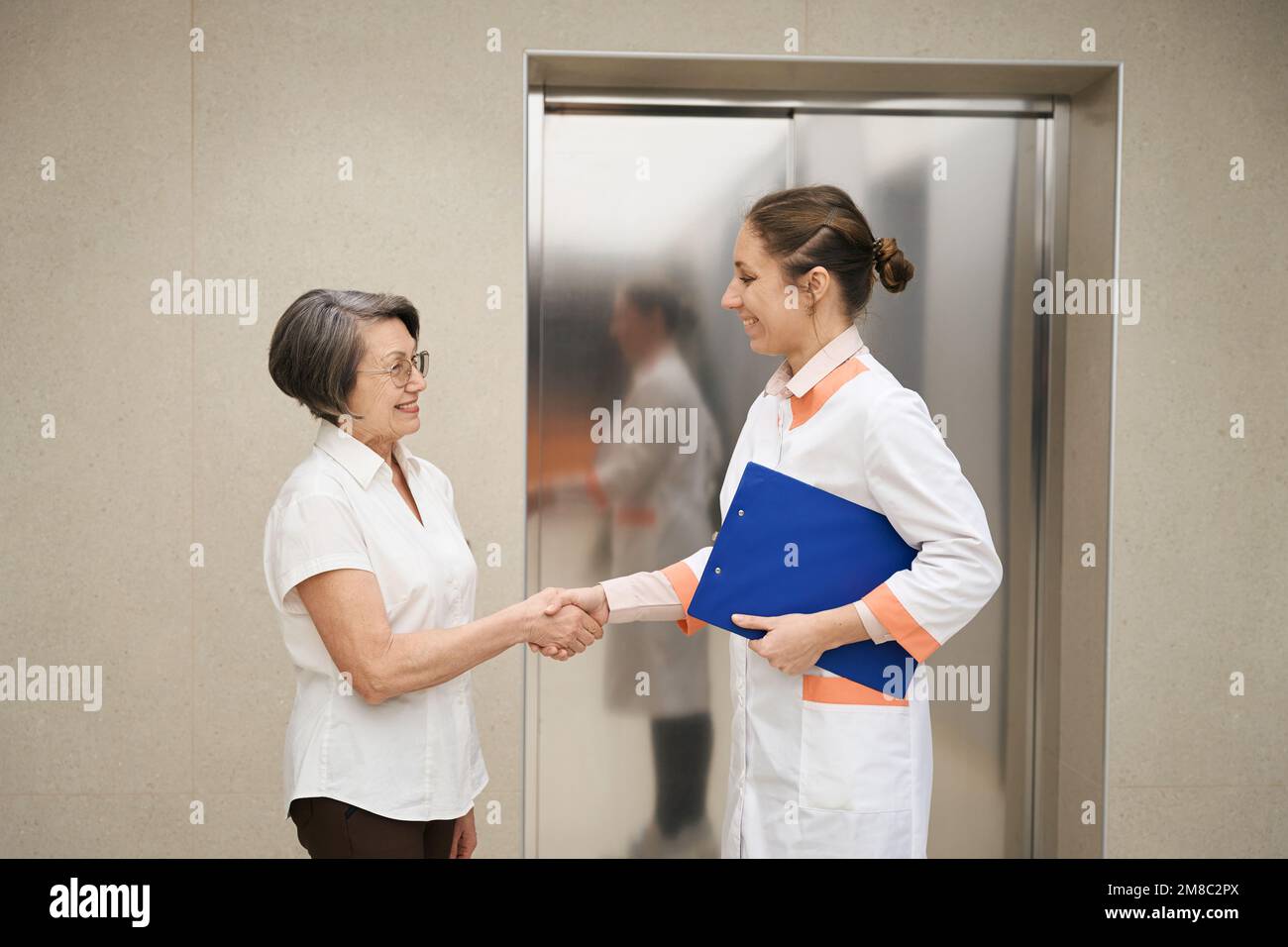 Doctor greets an elderly patient at the elevator in the lobby Stock ...