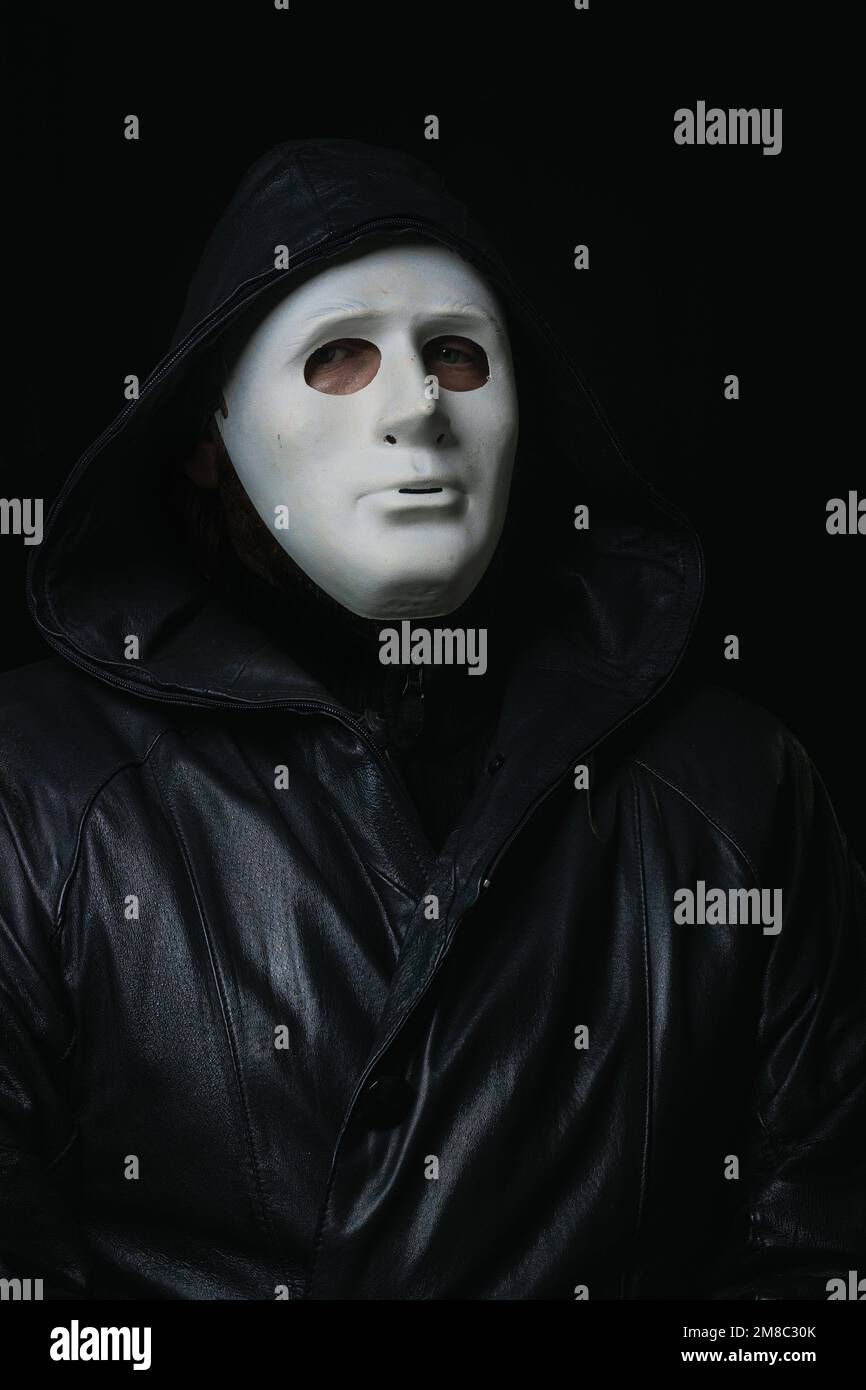 Man in terrible face mask staring at camera against dark background ...