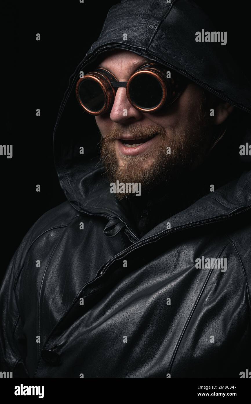 A man in a hood, wearing vintage steampunk goggles looking at the ...