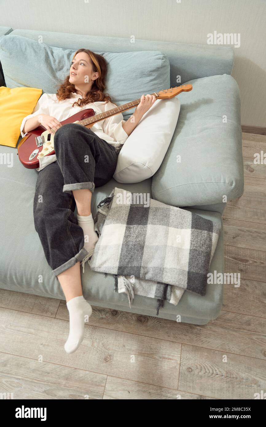 Pensive songwriter strumming stringed instrument in bedroom Stock Photo ...