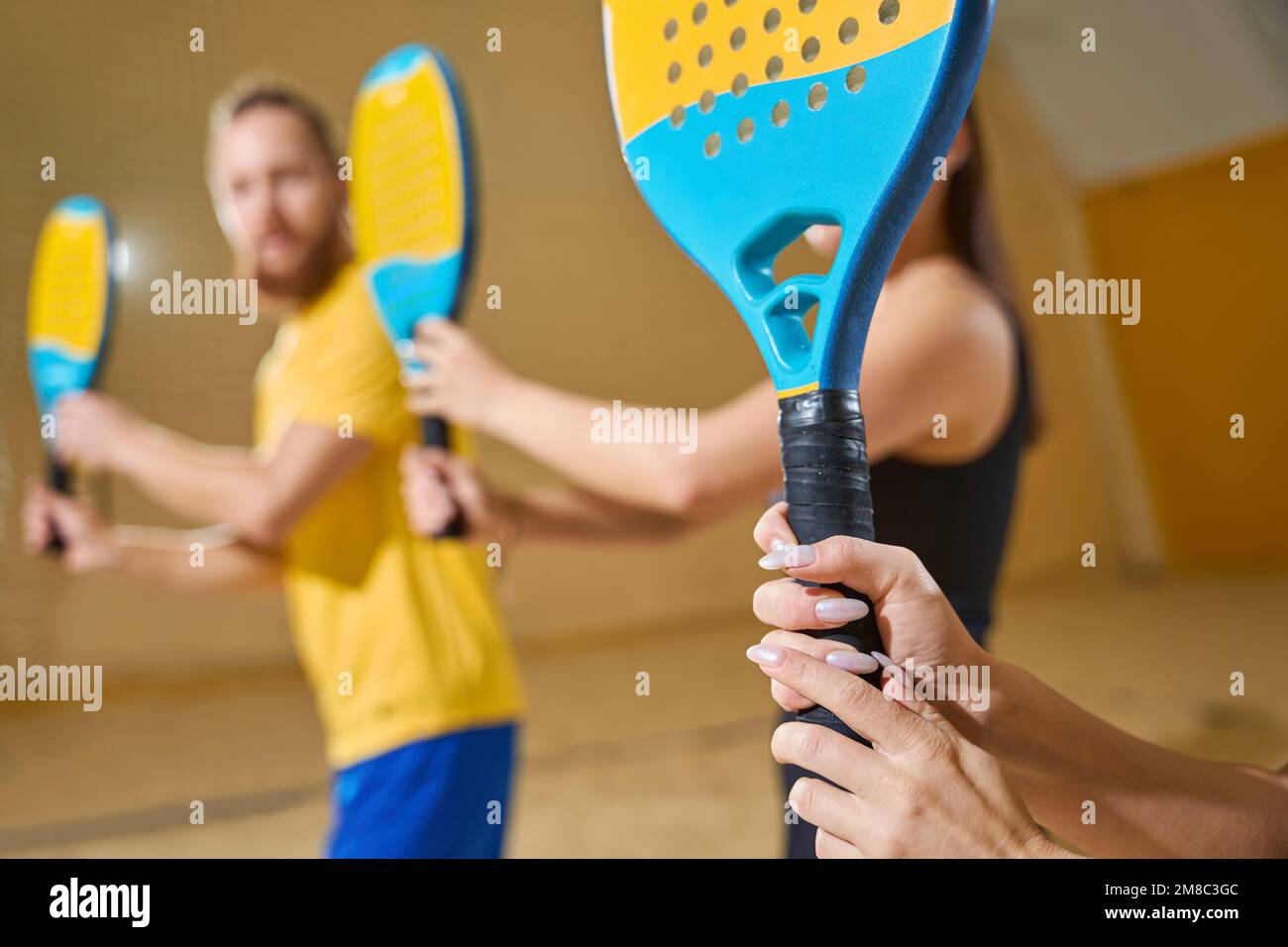 Two women are holding frescobol rackets next to a man Stock Photo - Alamy
