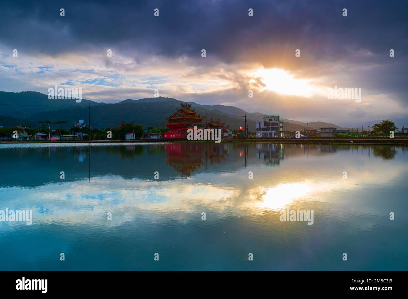 Beautiful sunset view of the countryside. Red temple, lake and ...