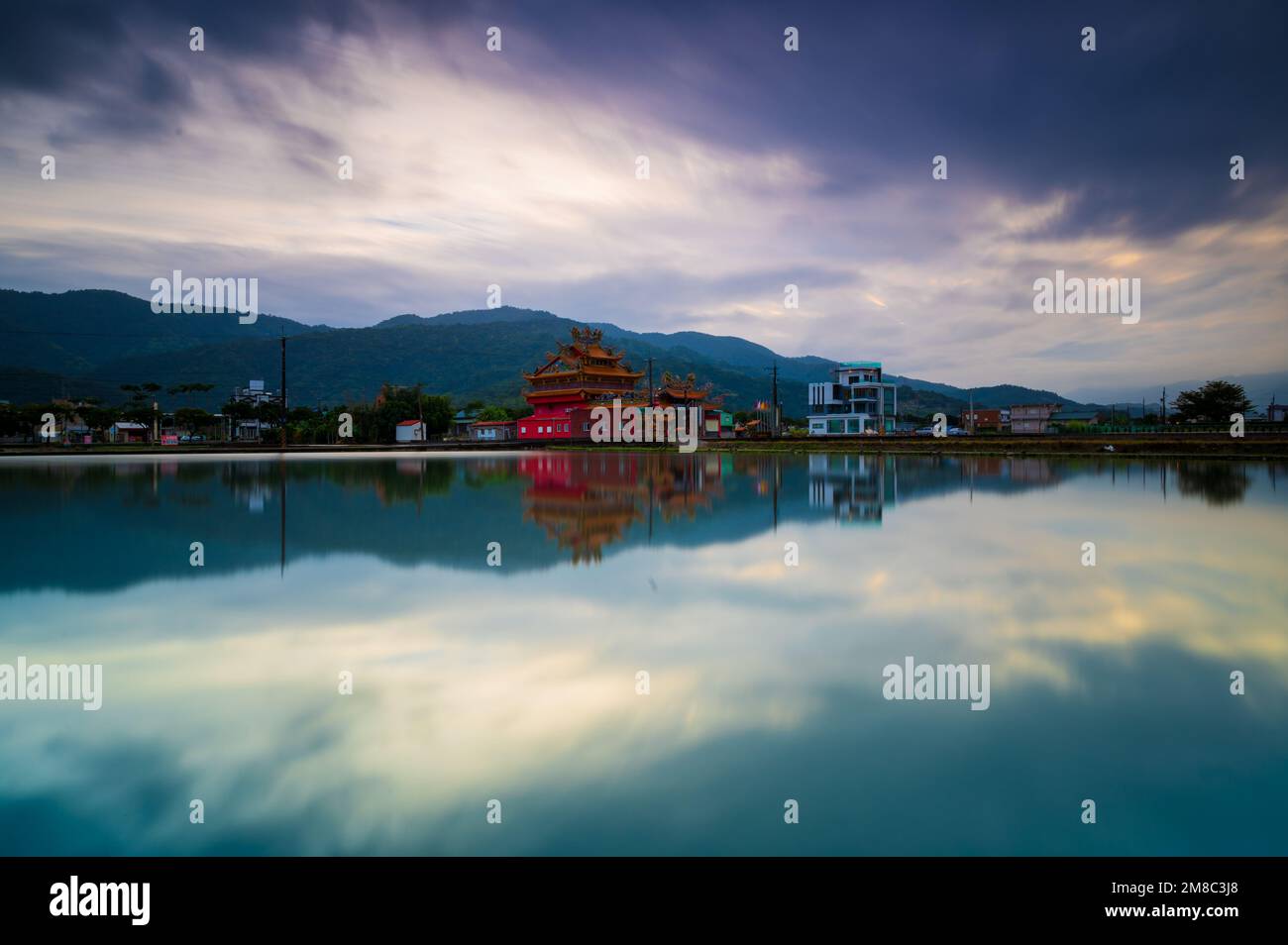 Beautiful sunset view of the countryside. Red temple, lake and ...