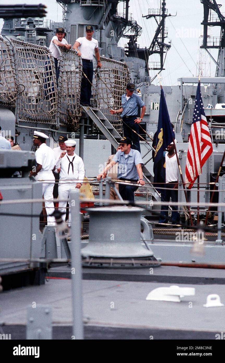 Officers and crew members aboard a U.S. Navy ship watch as supplies are ...