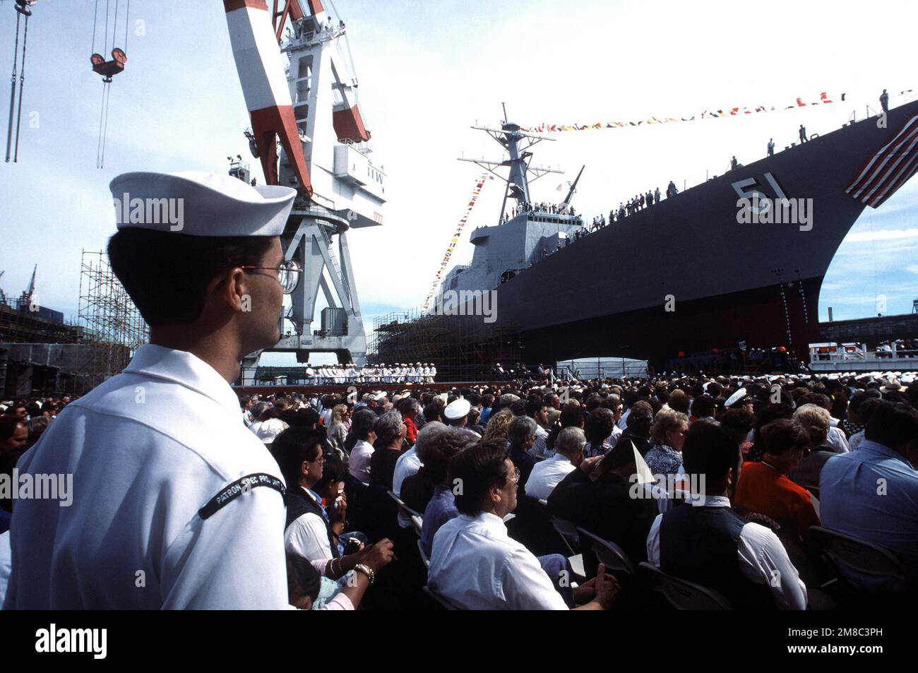 The guided missile destroyer ARLEIGH BURKE (DDG 51) towers over the ...