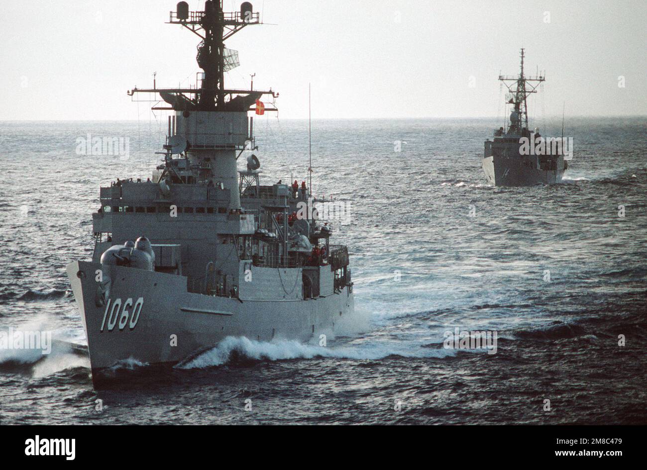 A bow view of the frigate USS LANG (FF 1060) followed by the guided ...