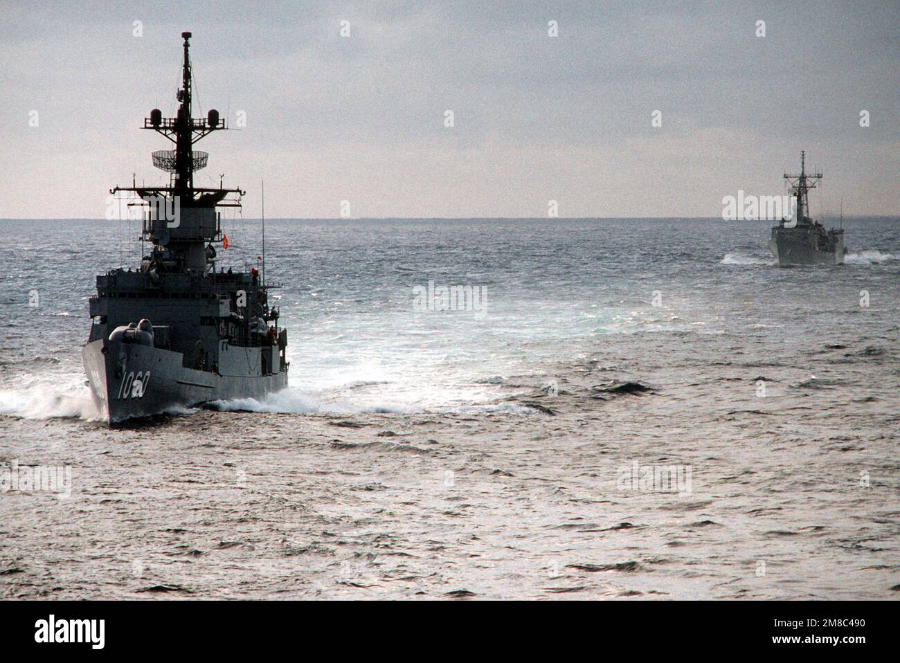 A bow view of the frigate USS LANG (FF 1060) followed by the guided ...