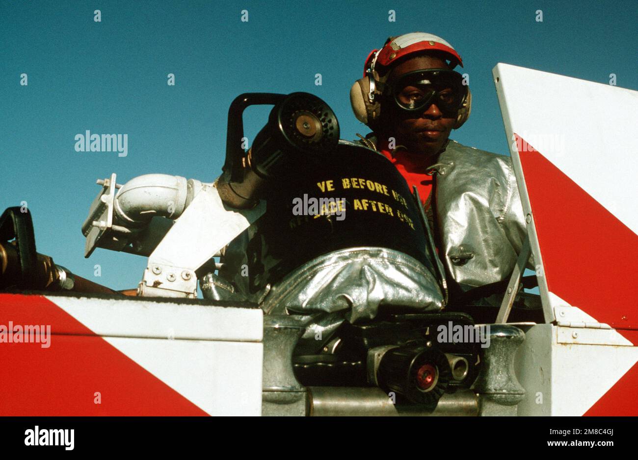 A sailor in a proximity suit stands by with fire-fighting equipment in ...