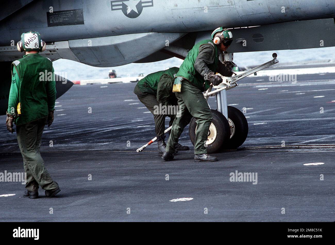 Catapult crew members position an F-14 Tomcat aircraft on a catapult on ...