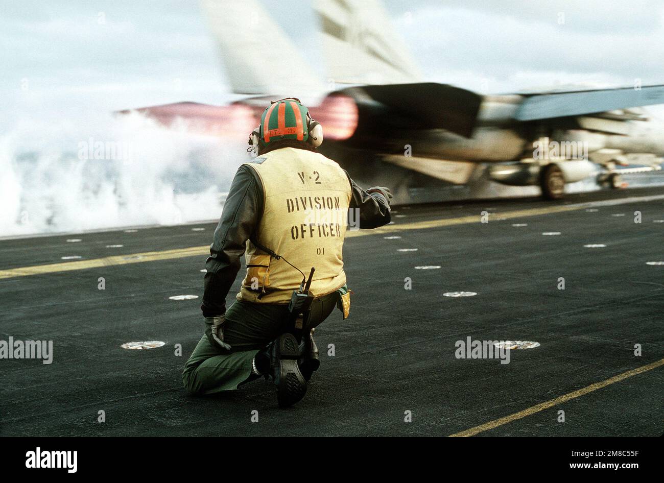 A flight deck crewman signals the launch of an F-14A Tomcat aircraft ...