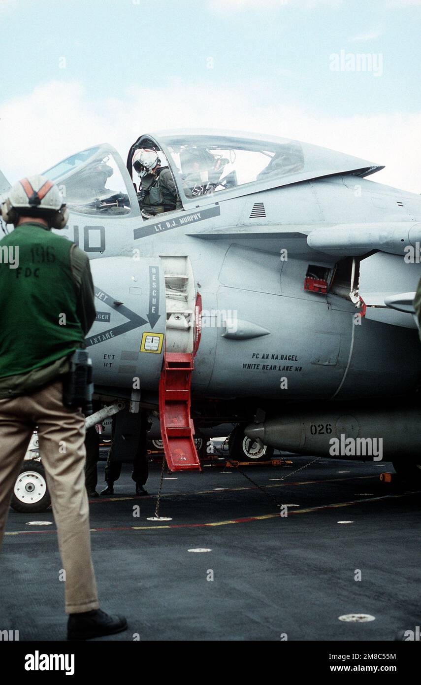 A catapult crew member stands by as the pilot closes the cockpit of an ...
