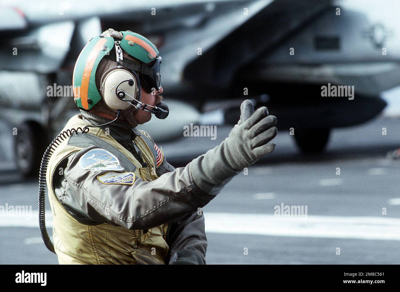 A catapult officer signals to a pilot on the flight deck of the ...