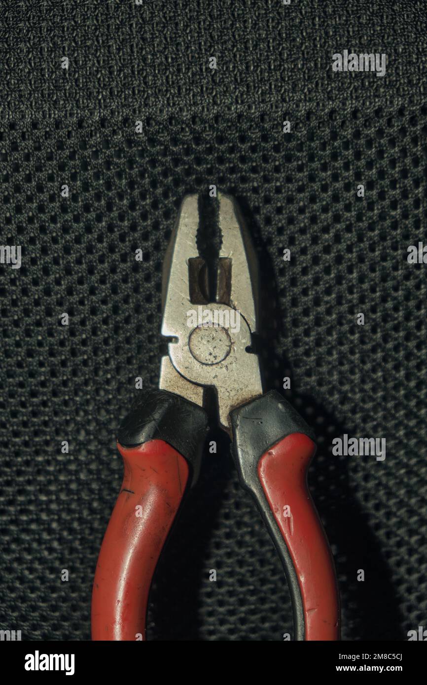 Pliers Open metal nippers with a red and green handle isolated on black ...