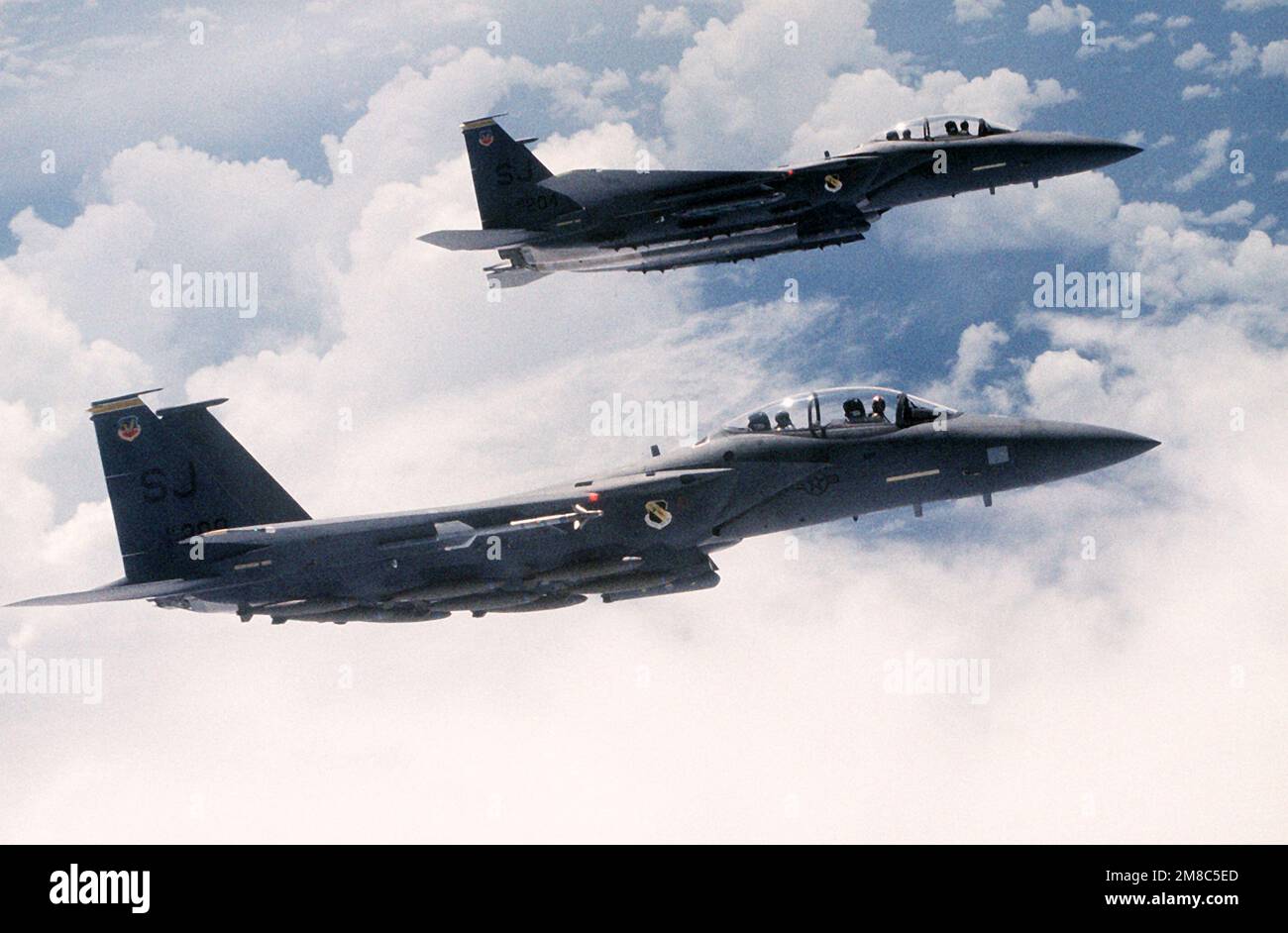 An air-to-air right side view of two F-15E Eagle aircraft. The plane in ...