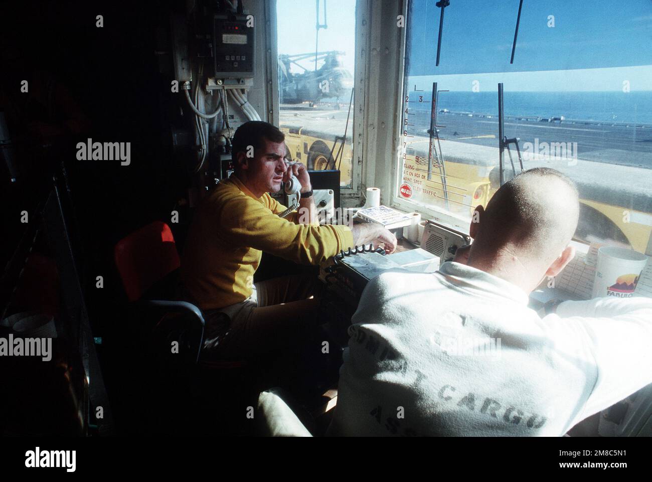Crew members monitor equipment in the flight control center aboard the ...